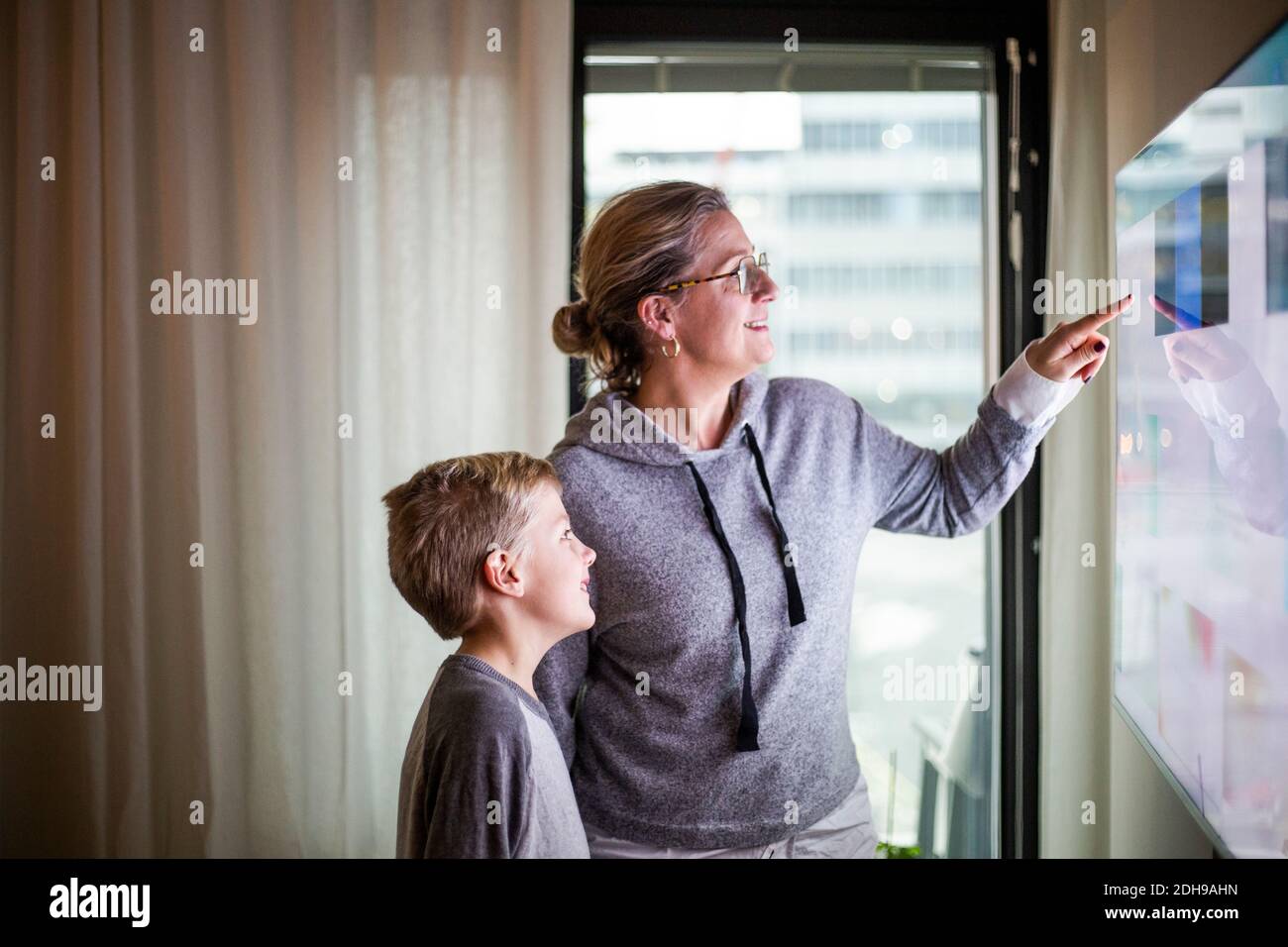 Mother guiding son in using smart TV at home Stock Photo - Alamy