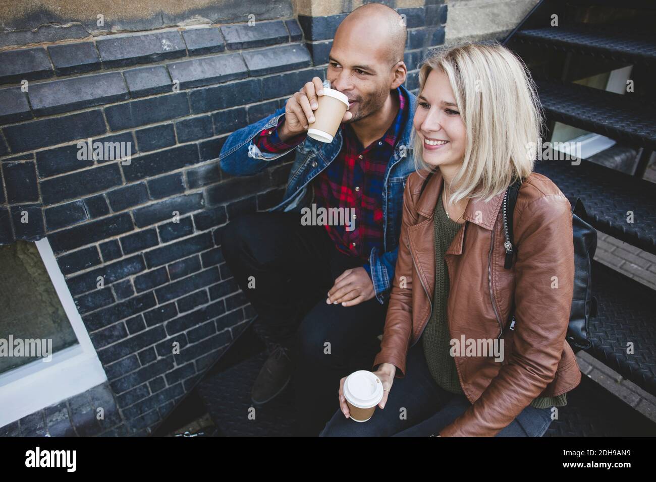 Couple having coffee while sitting on steps Stock Photo - Alamy