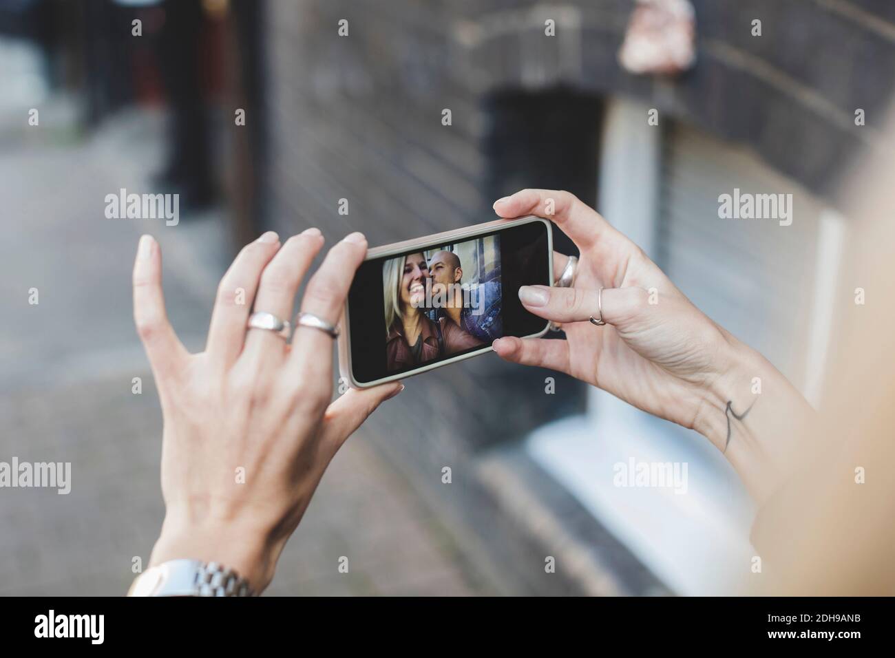Man kissing woman as she takes selfie through smart phone Stock Photo ...