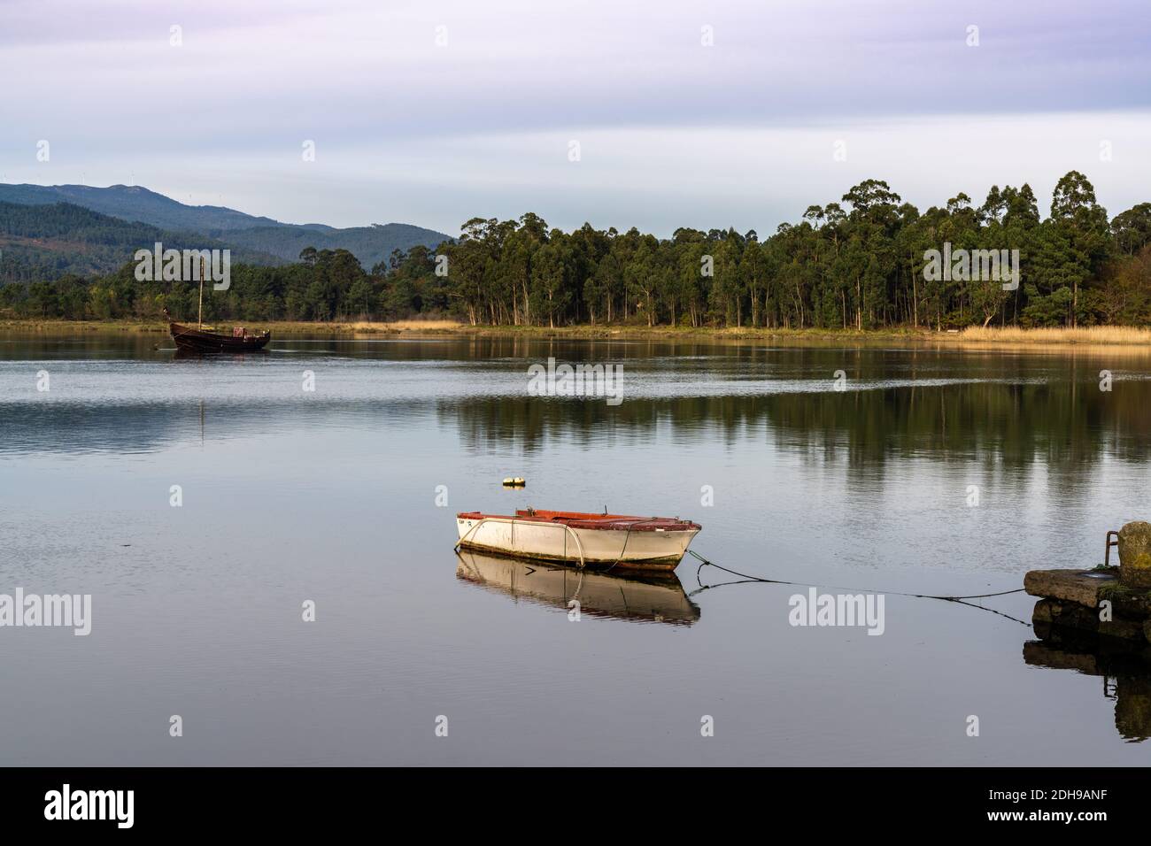 Two boats anchored on a calm and peaceful river with hills and ...