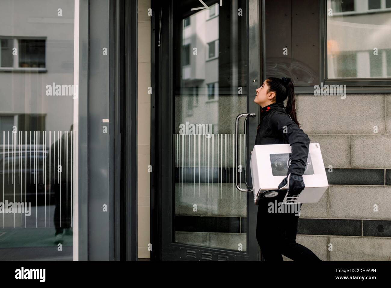 Young delivery woman delivering package at building Stock Photo - Alamy