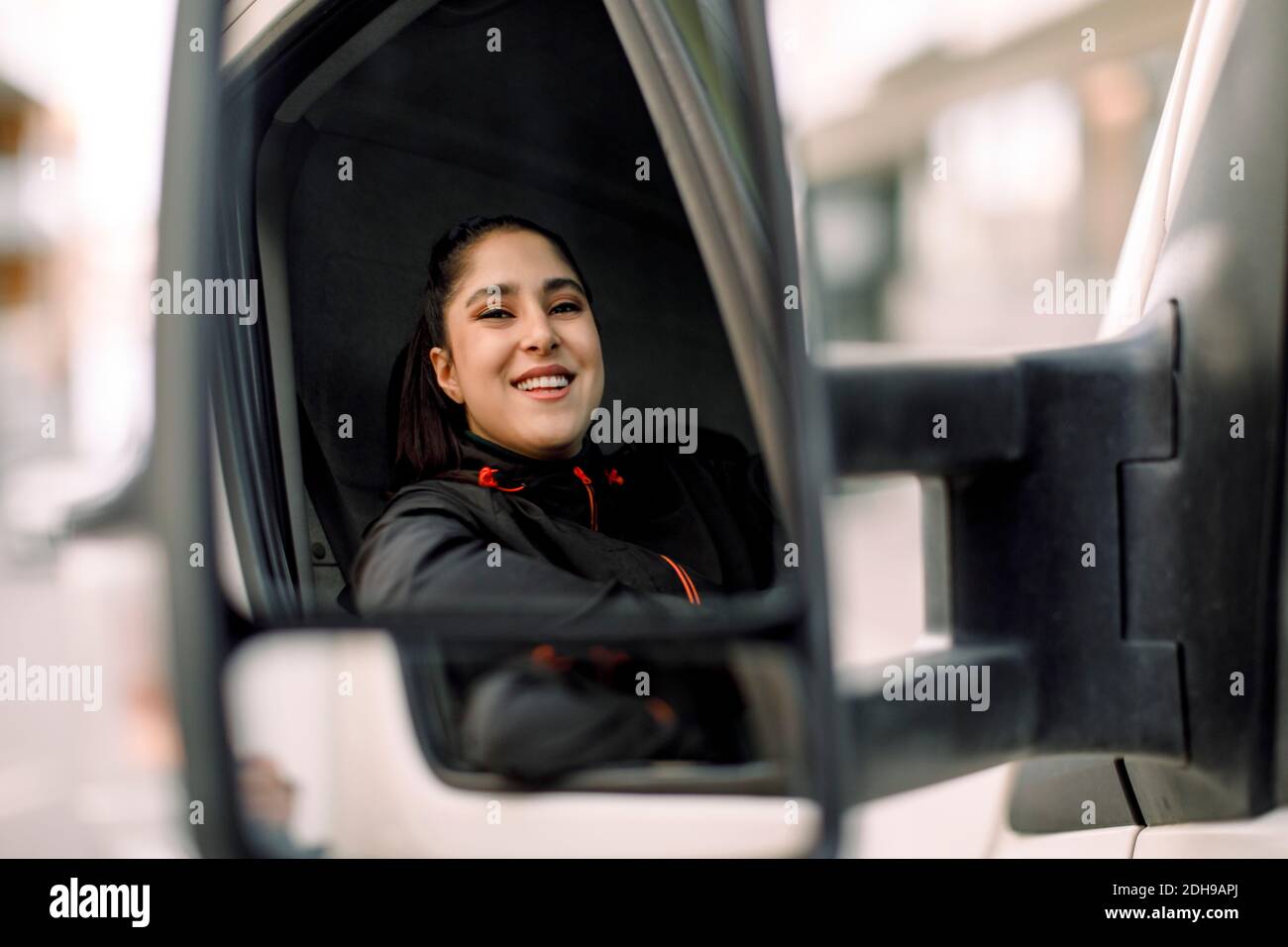 Portrait of smiling young delivery woman driving truck Stock Photo - Alamy