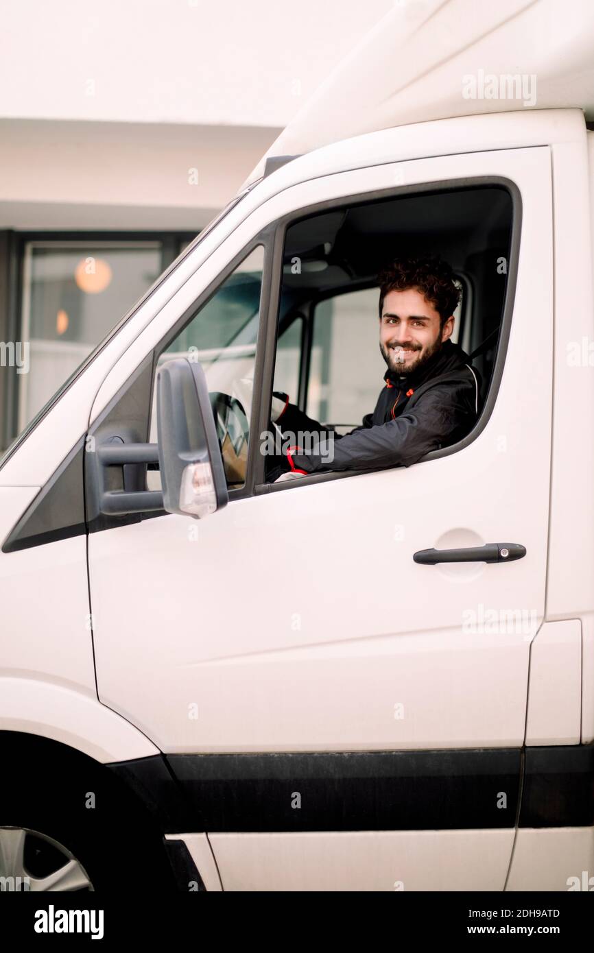 Portrait of smiling young delivery man driving truck Stock Photo - Alamy