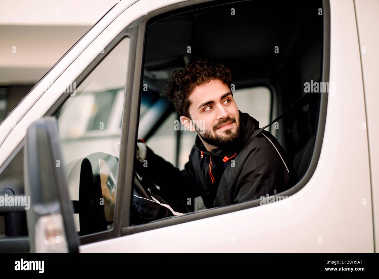 Young delivery man looking through window while driving truck Stock ...