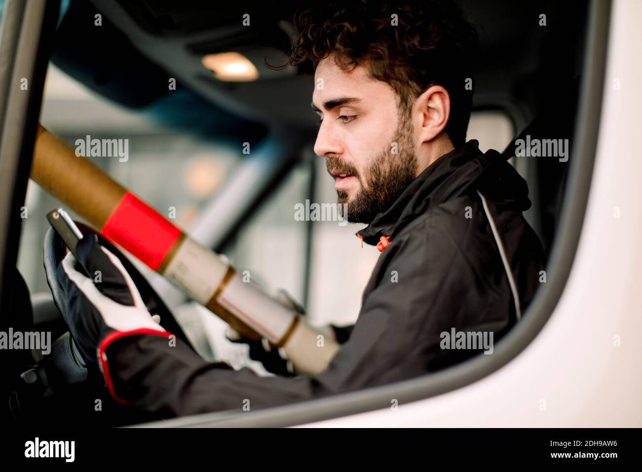 Young delivery man using mobile phone while driving truck Stock Photo ...