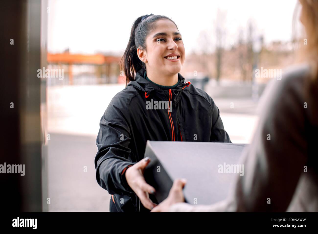 Delivery woman delivering package to customer Stock Photo - Alamy