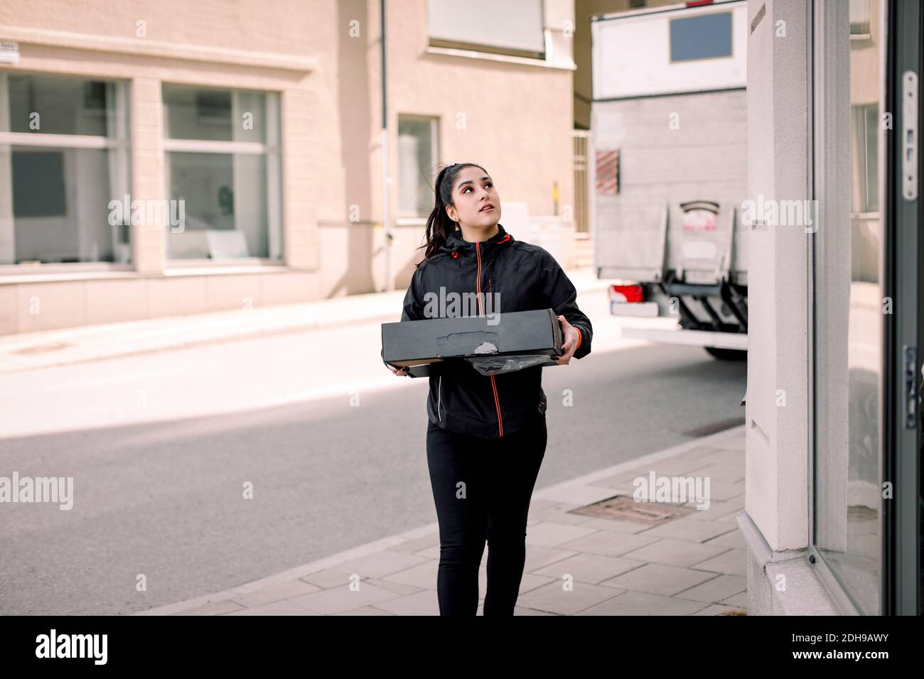 Young delivery woman delivering package at building Stock Photo - Alamy