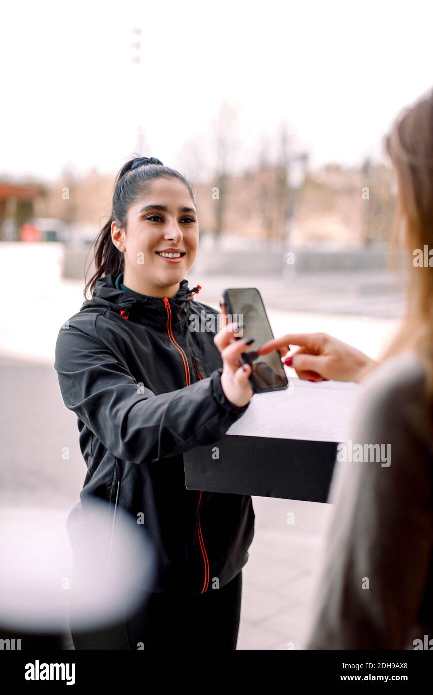 Customer signing on smart phone while receiving package from delivery ...