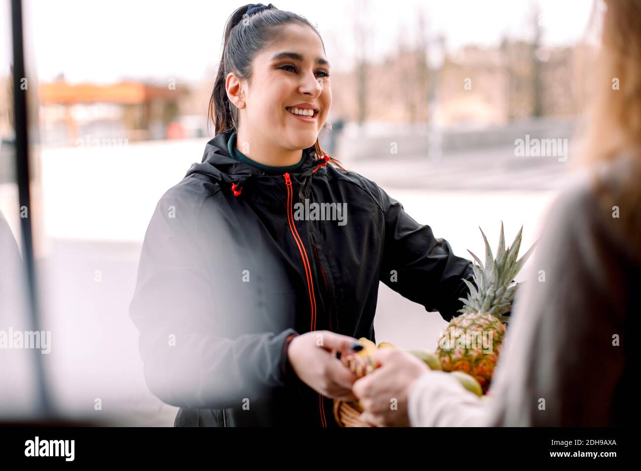 Delivery woman delivering fruits to female customer Stock Photo - Alamy