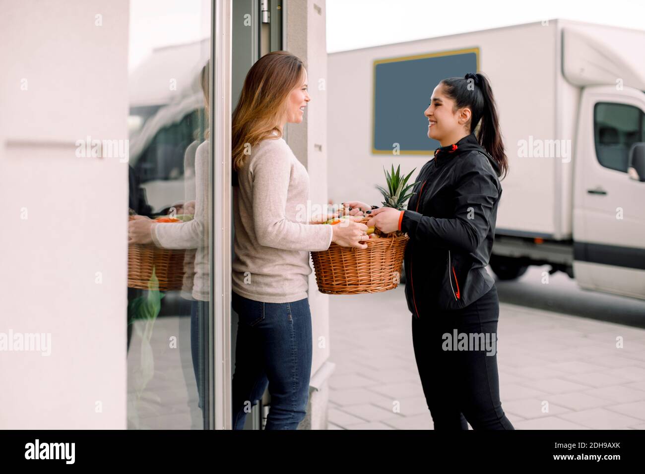 Delivery woman delivering fruits to mature female customer Stock Photo ...