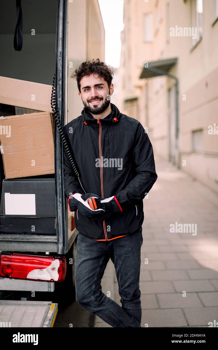 Portrait of confident young delivery man with boxes in truck Stock ...