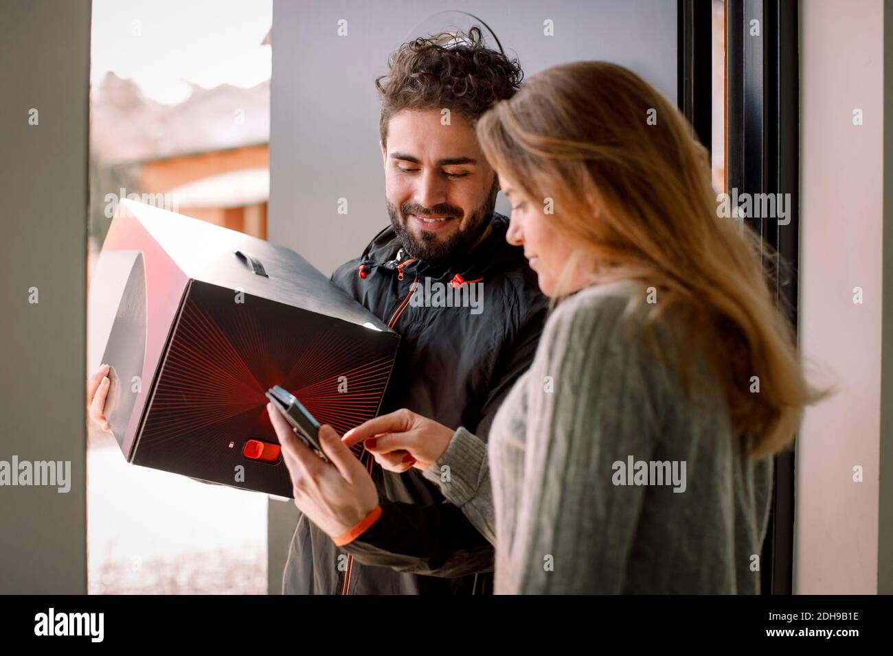 Female customer signing on smart phone while receiving package from ...