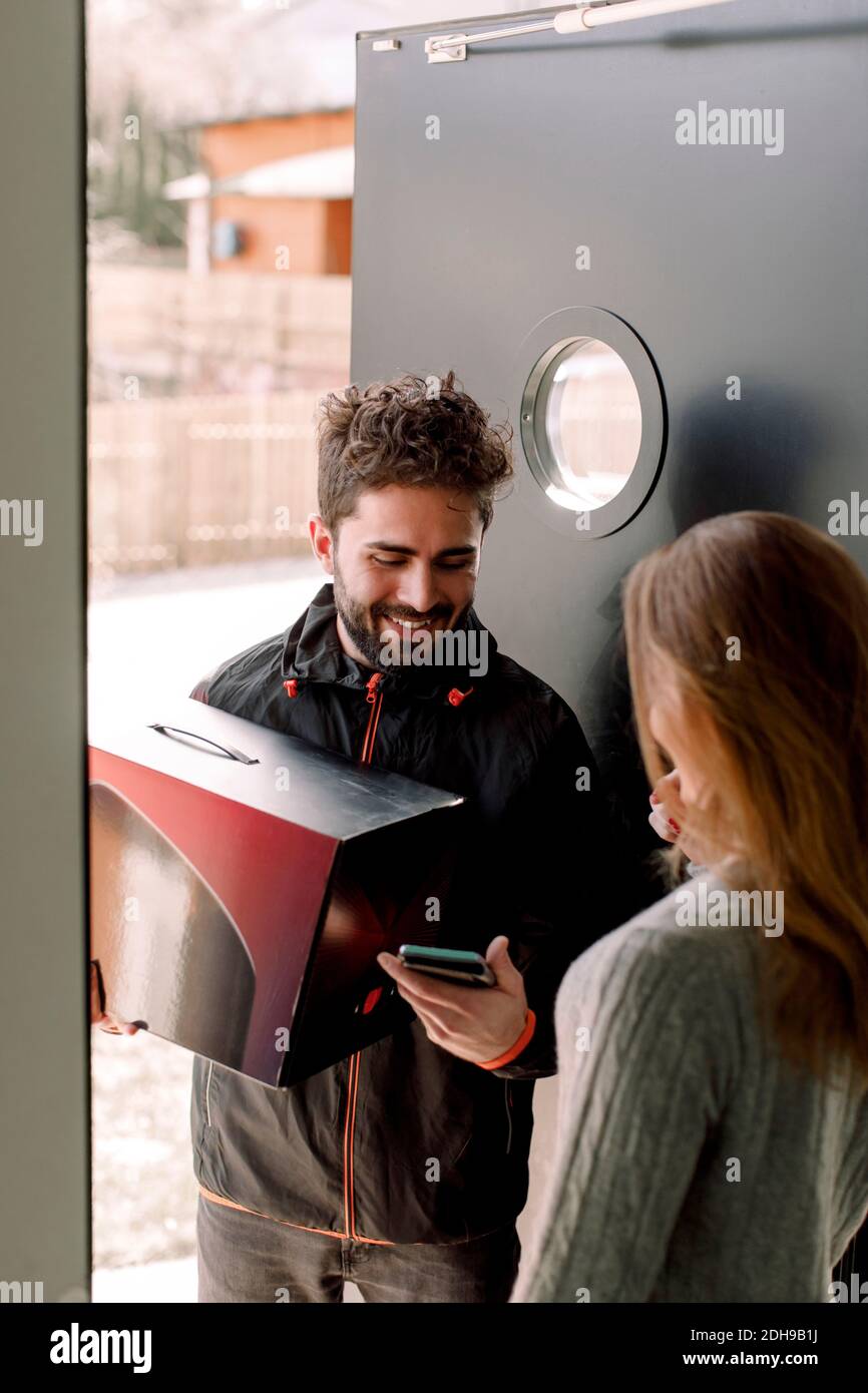 Female customer receiving package from delivery man Stock Photo - Alamy