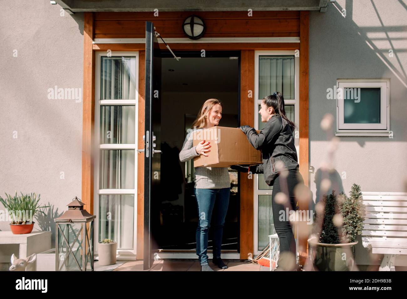 Female customer receiving box from young delivery woman Stock Photo - Alamy