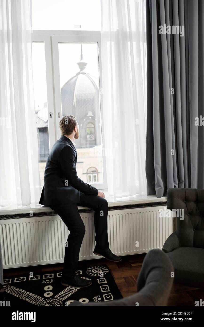 Businessman sitting on window sill looking at dome in hotel room Stock ...