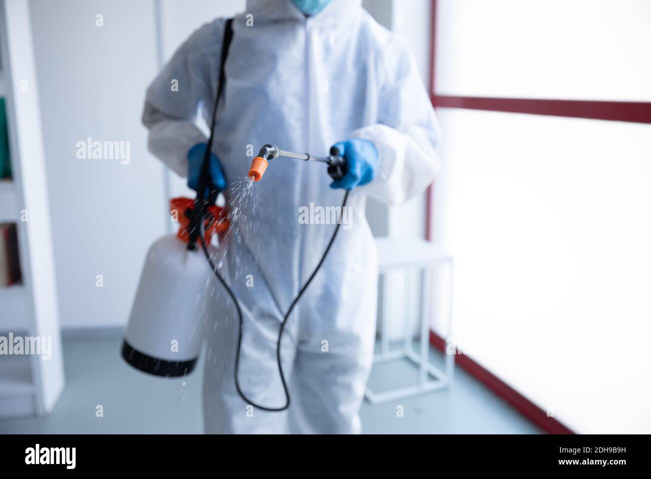 Mid section of health worker wearing protective clothes cleaning using ...