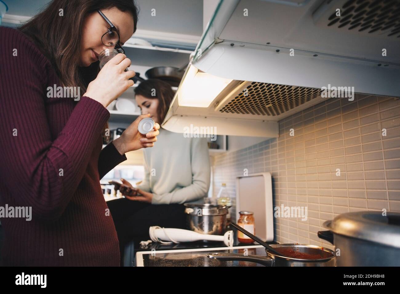 Woman smelling ingredient in bottle while cooking food Stock Photo - Alamy