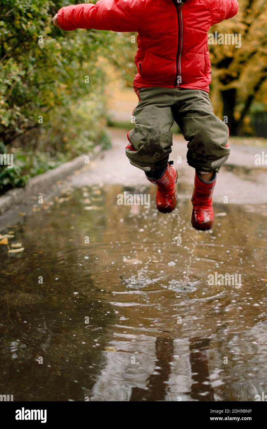 Boy jumping in puddle on road Stock Photo - Alamy