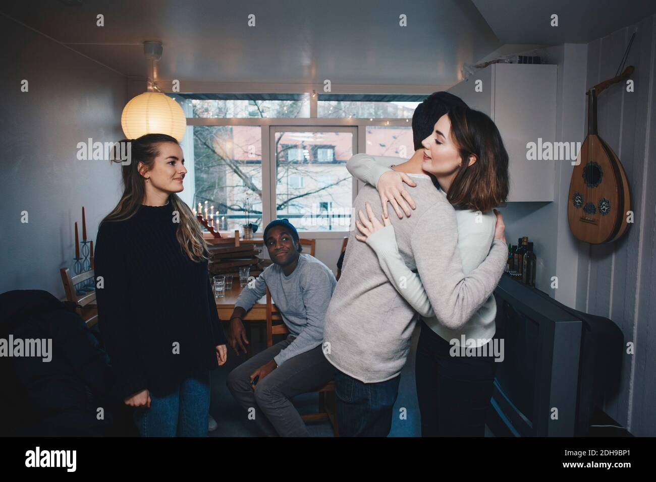 Friends looking at man and woman hugging in college dorm room Stock ...