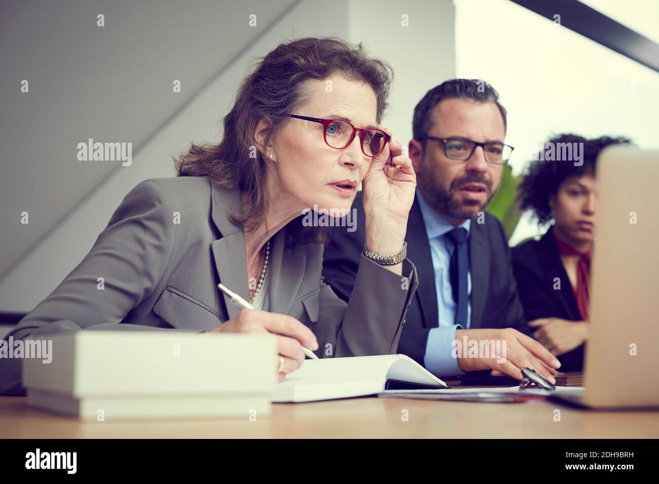 Confident senior female lawyer sitting by colleagues at office Stock ...