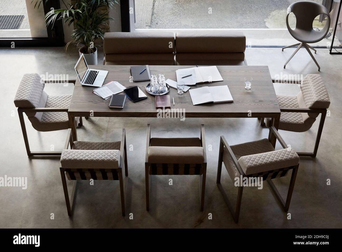 High angle view of documents and laptop on desk amidst chairs at office ...