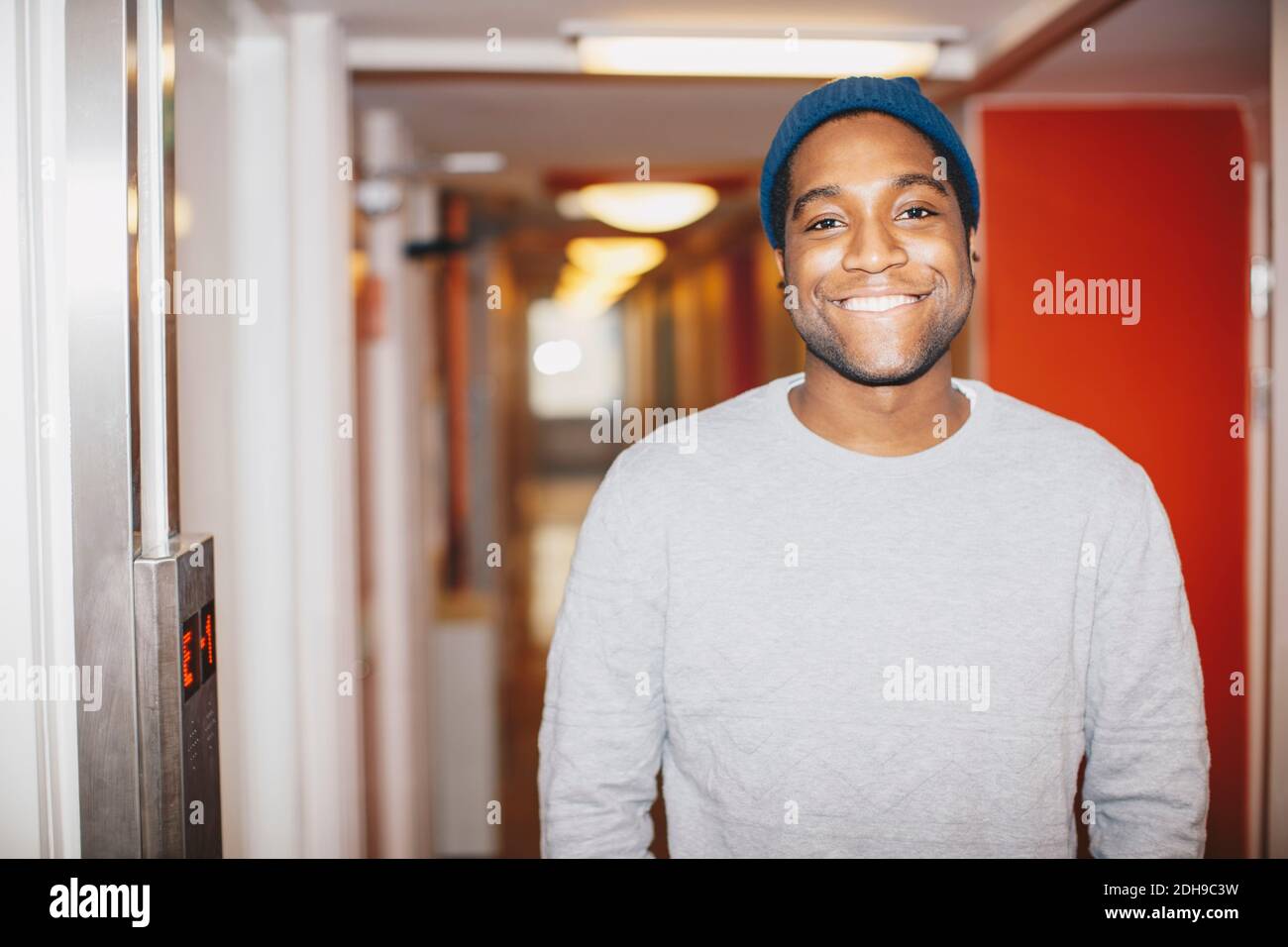 Portrait of happy man standing in college dorm corridor Stock Photo - Alamy