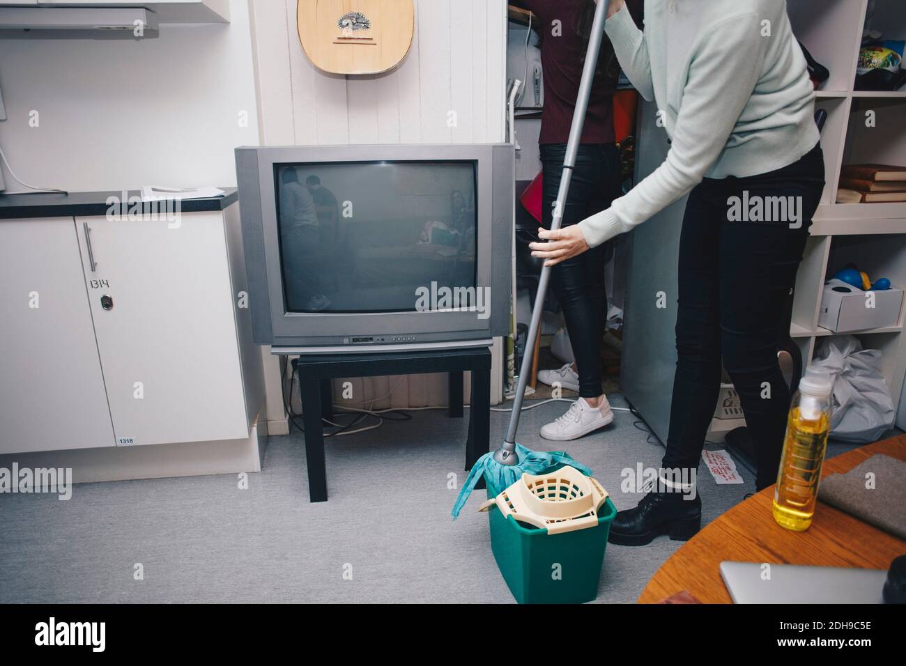 Low section of woman holding mop in bucket at college dorm Stock Photo ...