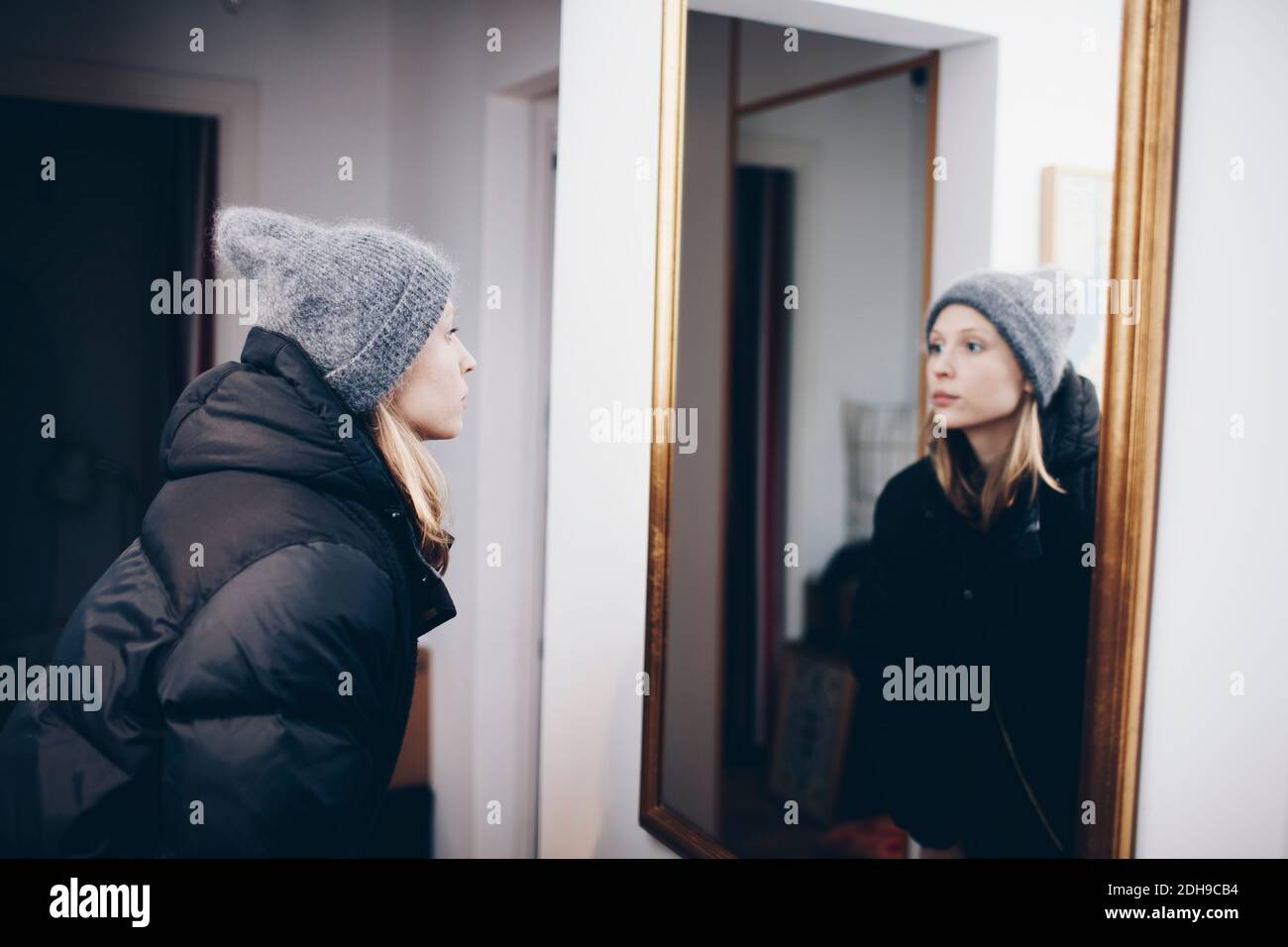 Woman looking at reflection in mirror on wall Stock Photo - Alamy