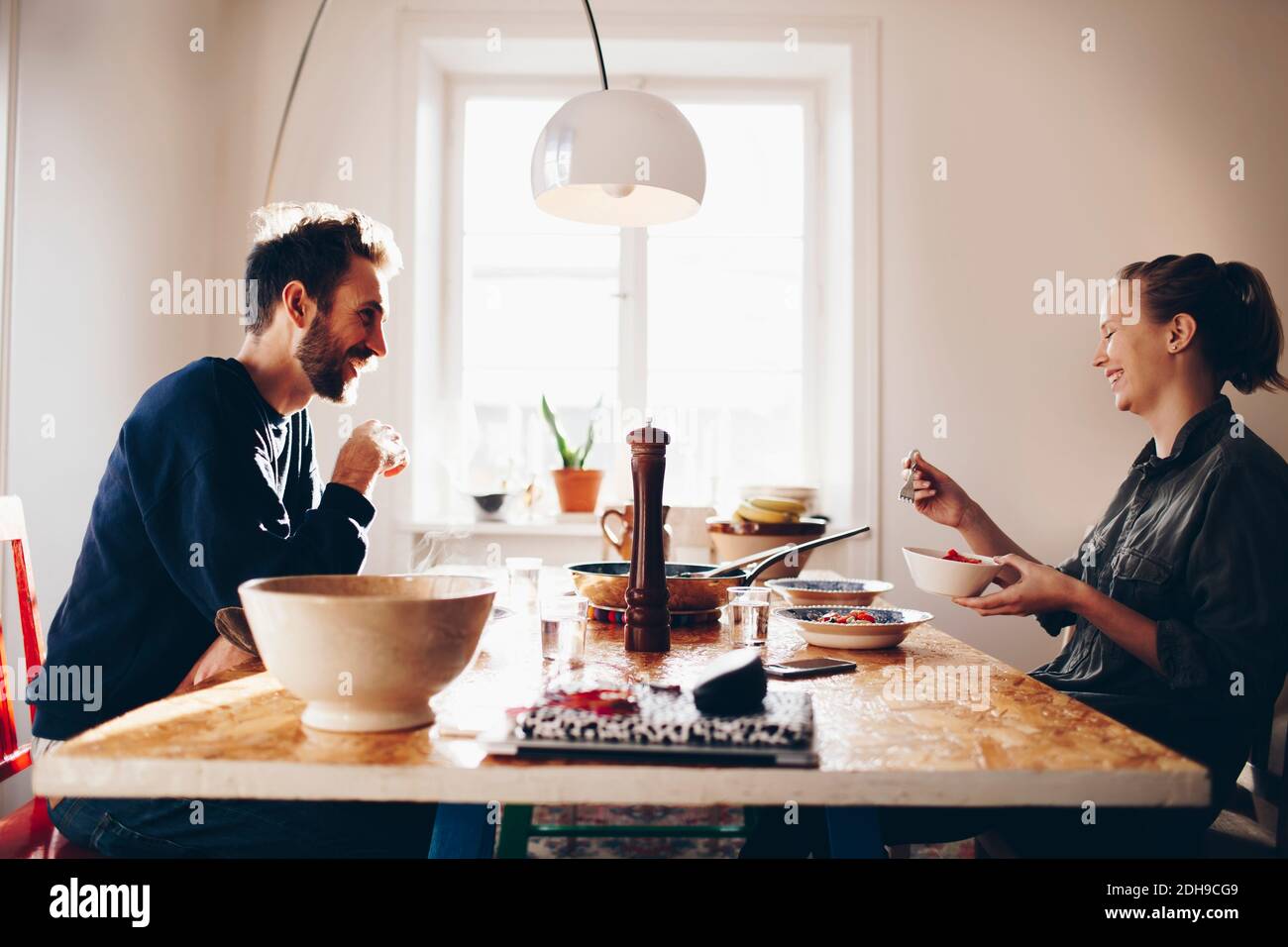 Side view of happy couple talking while eating lunch at home Stock ...