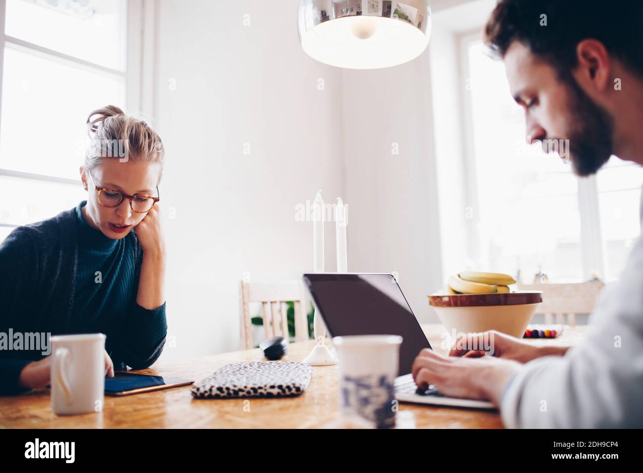 Couple using technologies at dining table while working from home Stock ...