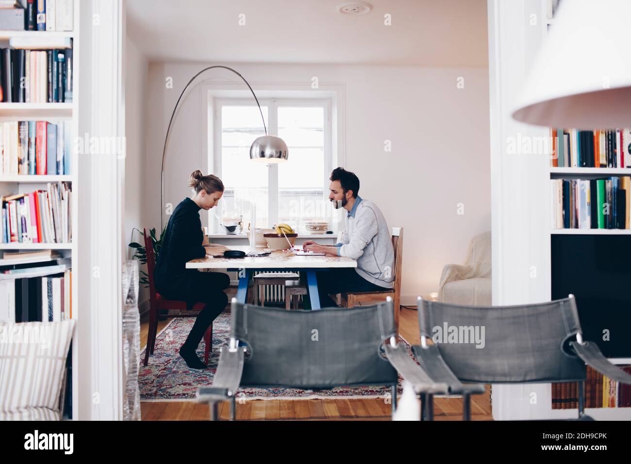 Side view of couple sitting at dining table working from home Stock ...