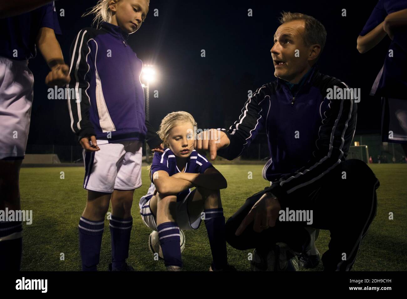 Coach explaining strategy to girls on soccer field at night Stock Photo ...