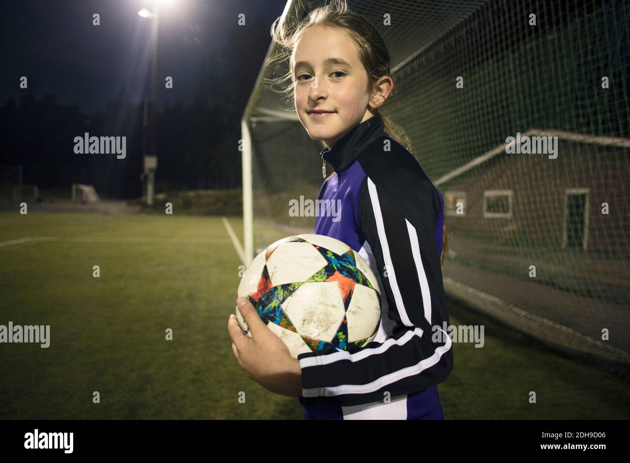 Portrait of girl with soccer ball standing against goal post Stock ...