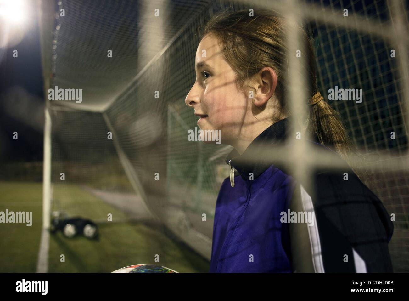 Side view of girl with soccer ball seen through goal post net Stock ...