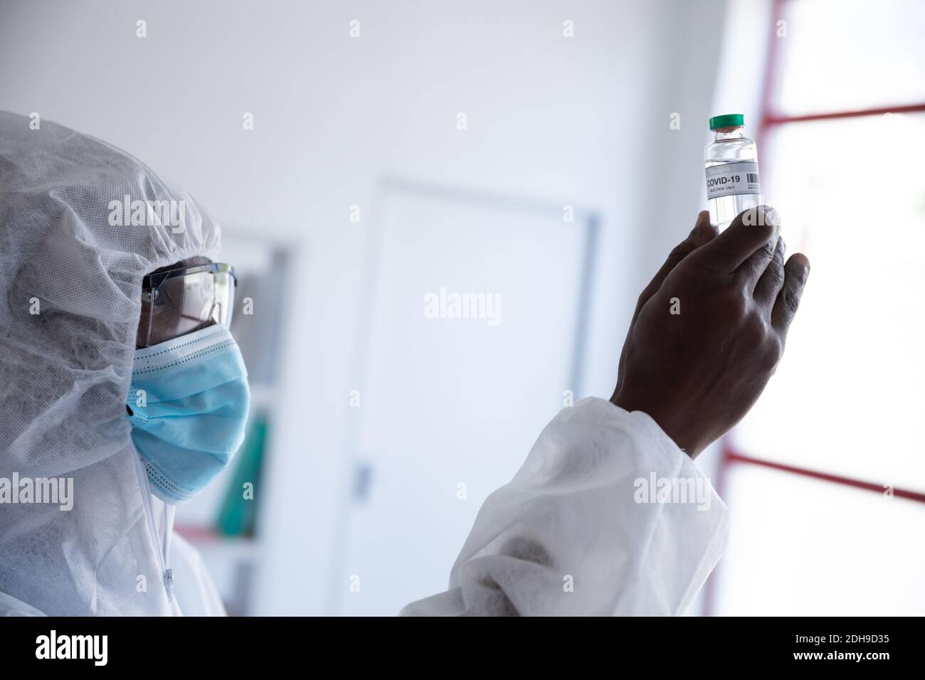 Health worker wearing protective clothes holding a vial bottle Stock ...