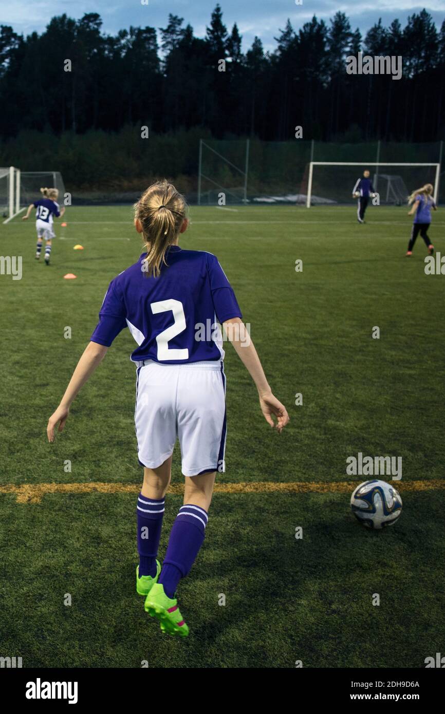 Rear view of girl playing with soccer ball on field Stock Photo - Alamy