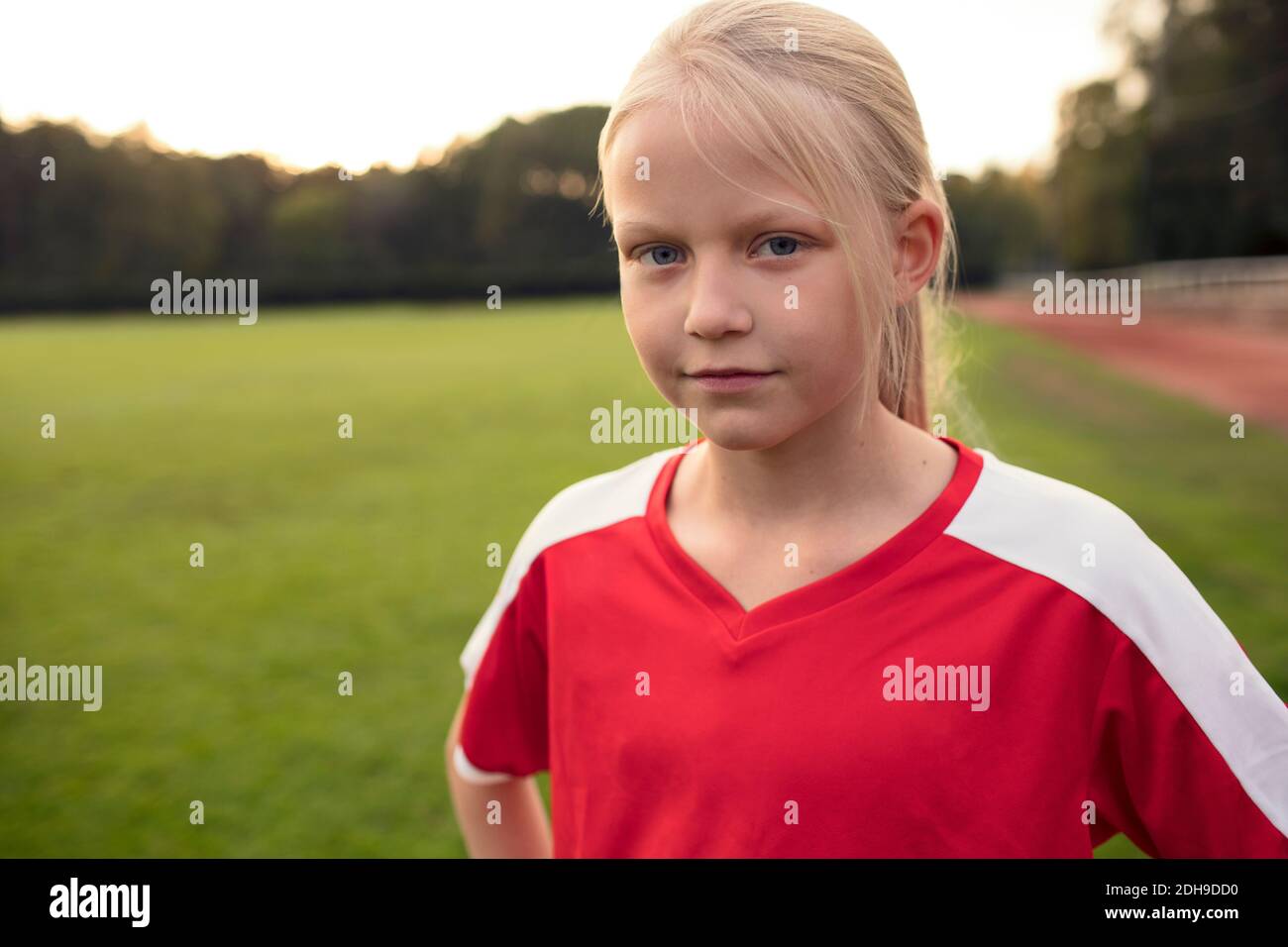Portrait of confident girl standing on soccer field Stock Photo - Alamy
