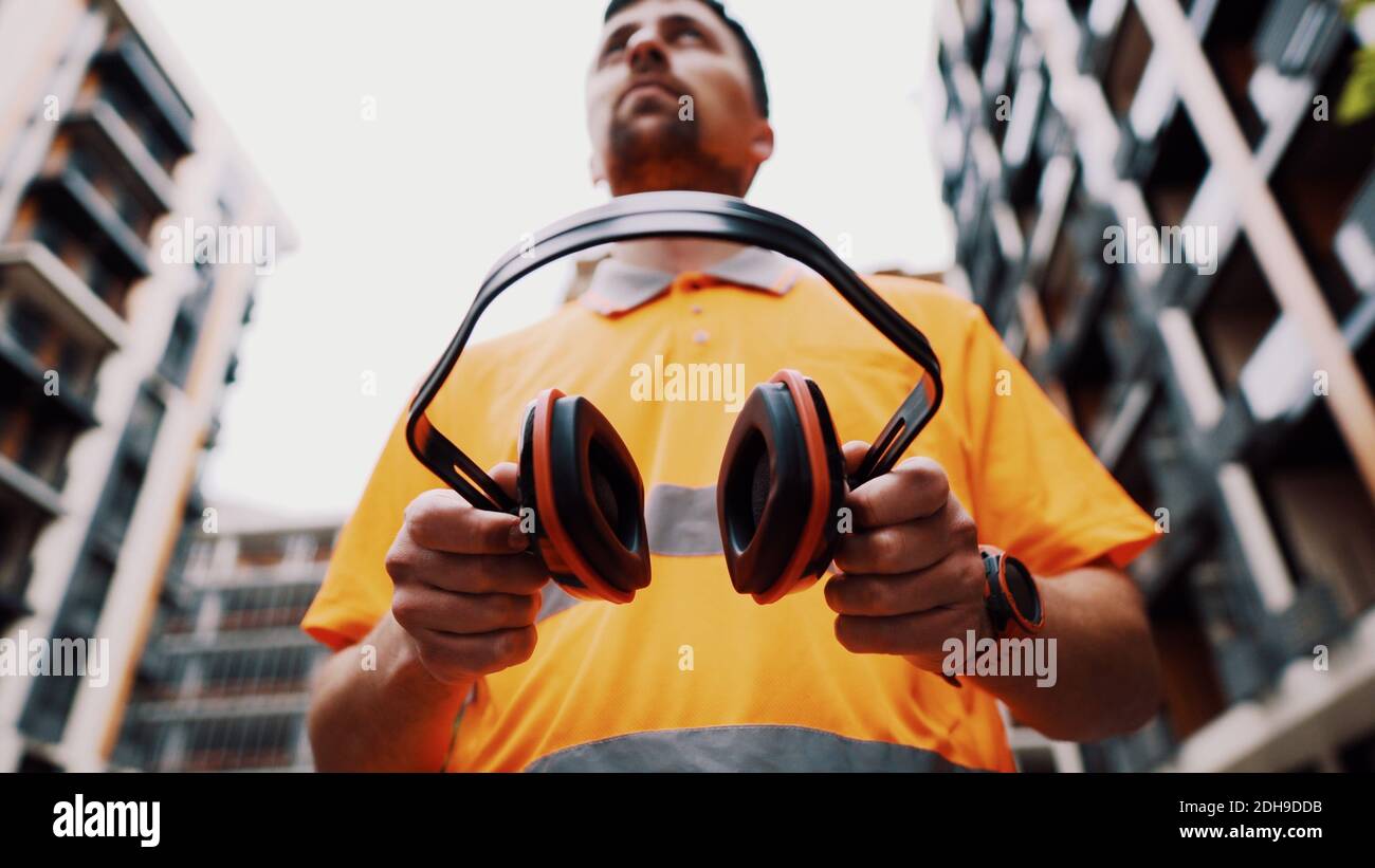 Builder covers his ears, ear muff to protect workers ears. Construction ...