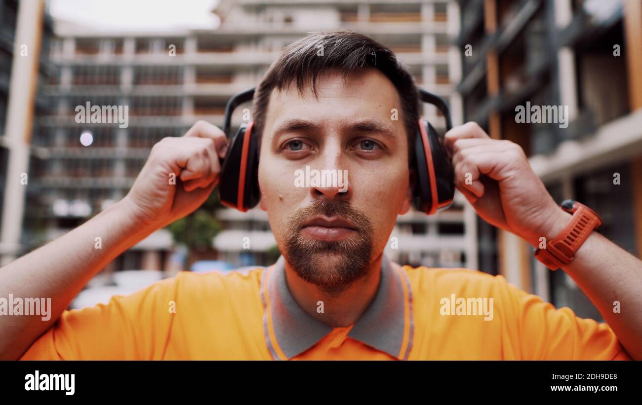 Builder covers his ears, ear muff to protect workers ears. Construction ... Builder covers his ears, ear muff to protect workers ears. Construction ...