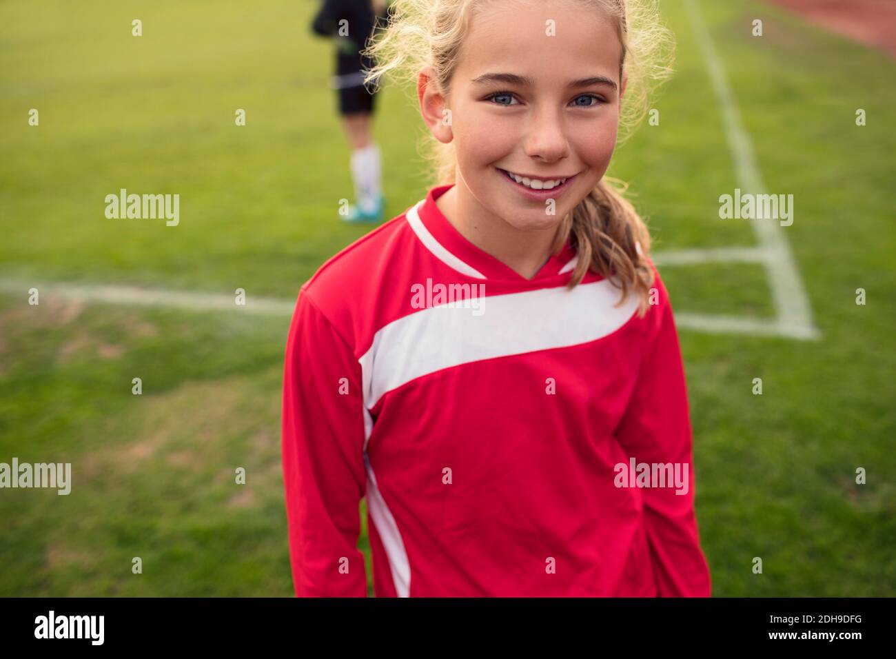 Portrait of happy girl standing on soccer field Stock Photo - Alamy