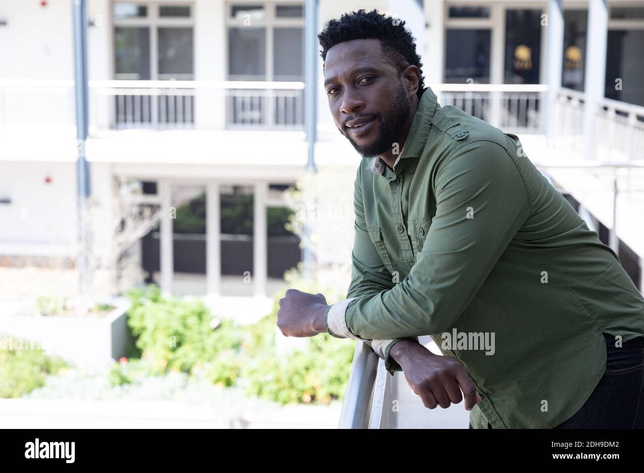 Portrait of Businessman leaning on railing in balcony at modern office ...