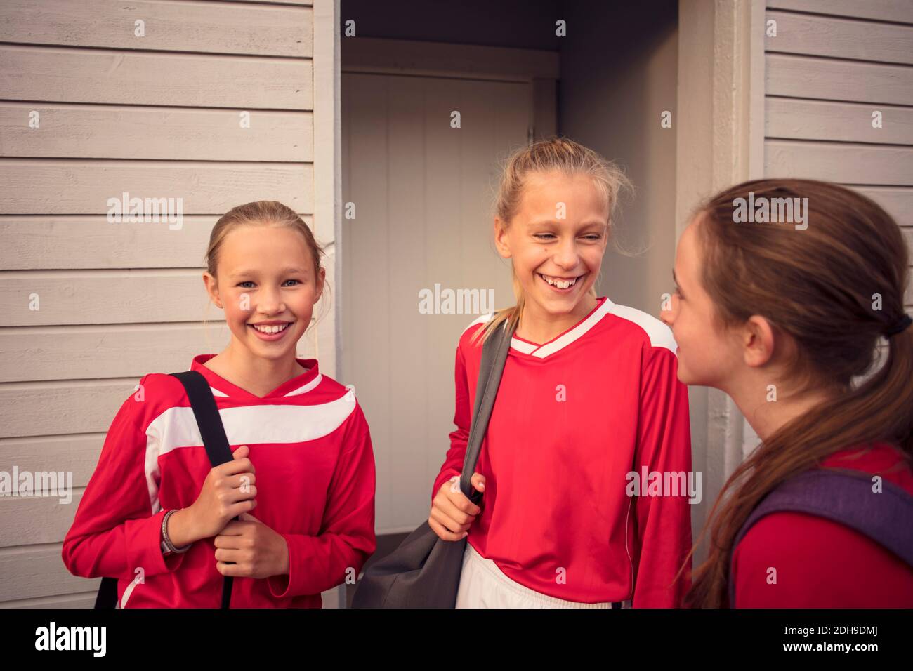 Happy girls talking while standing against wall Stock Photo - Alamy