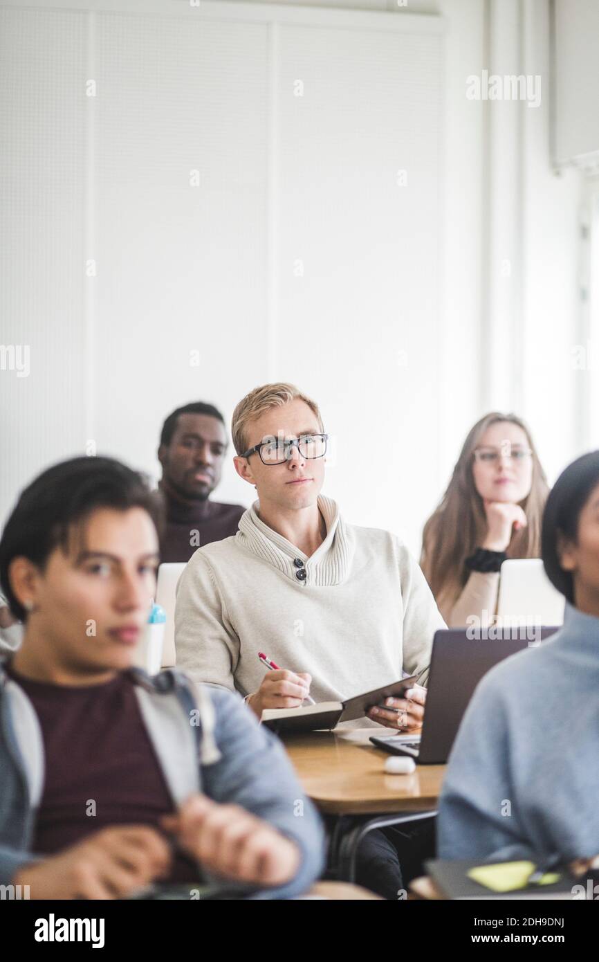 Young man sitting at desk in classroom Stock Photo - Alamy