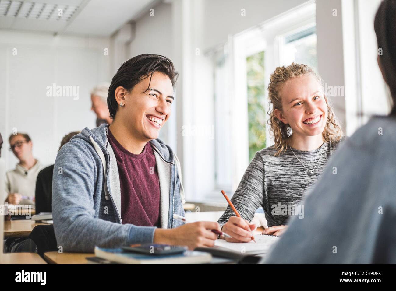 Smiling young man with female friend in classroom Stock Photo - Alamy