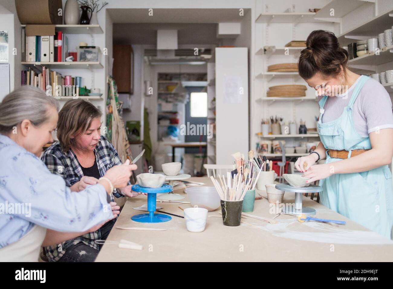 Female potters molding clay at workbench in store Stock Photo - Alamy
