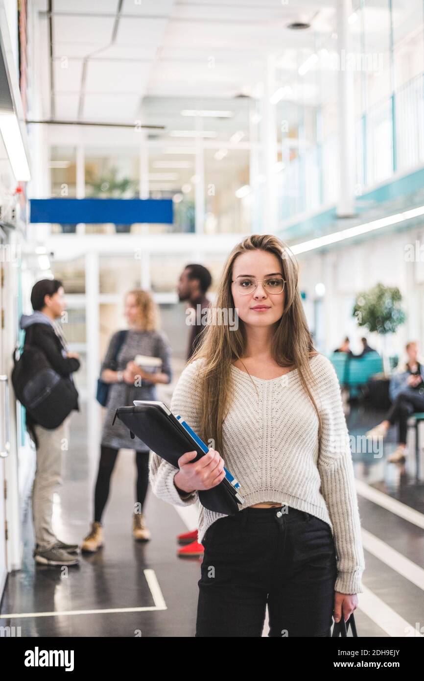 Portrait of confident female student standing in cafeteria at ...