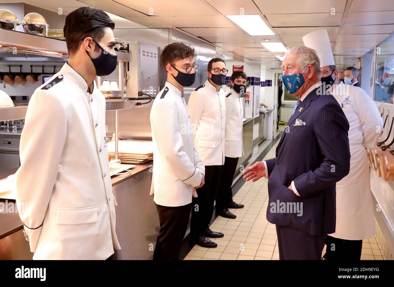 The Prince of Wales wears a face mask as he speaks to staff during a ...