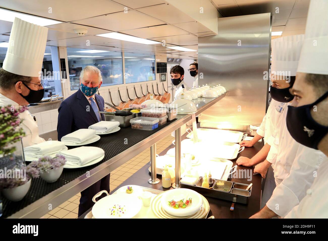 The Prince of Wales wears a face mask as he speaks to staff during a ...