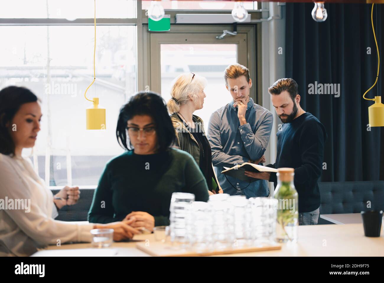 Business colleagues reading book in brightly lit office Stock Photo - Alamy