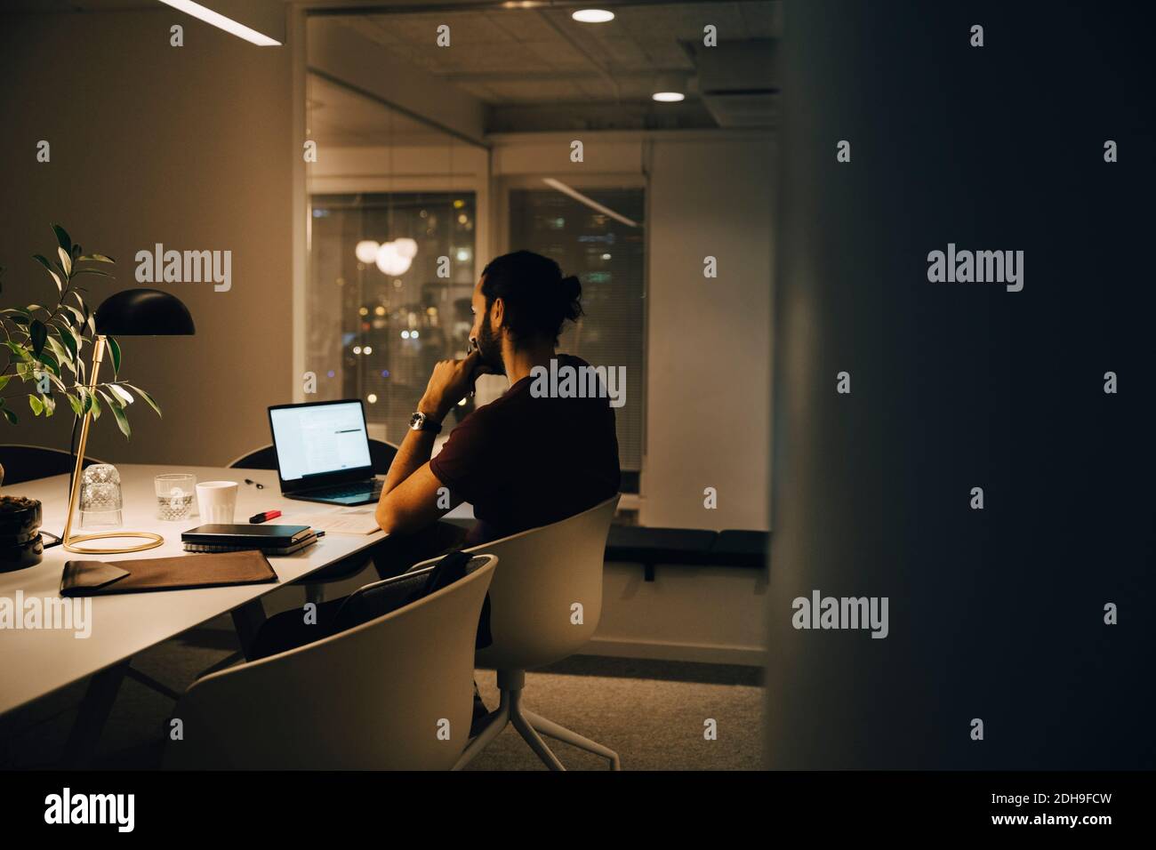 Side view of dedicated male professional working late at illuminated ...
